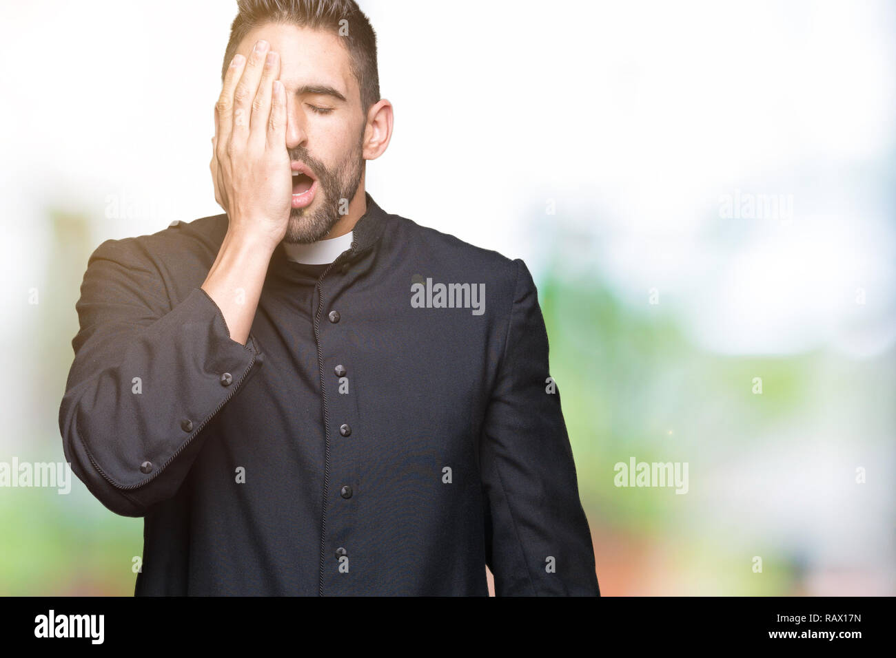 Young Christian priest over isolated background Yawning tired covering ...