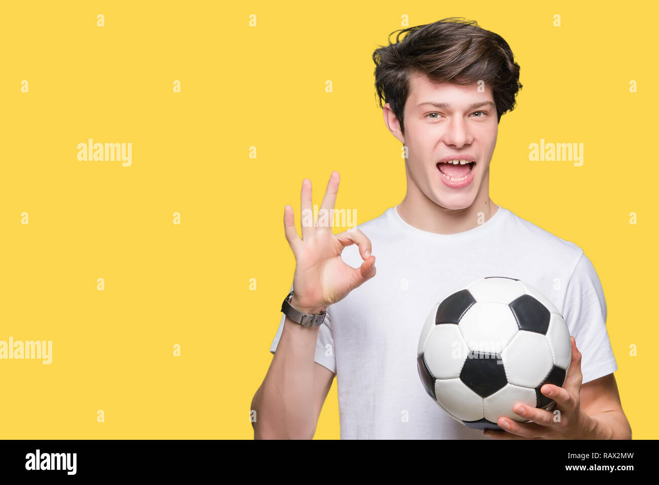 Young man holding soccer football ball over isolated background doing ...