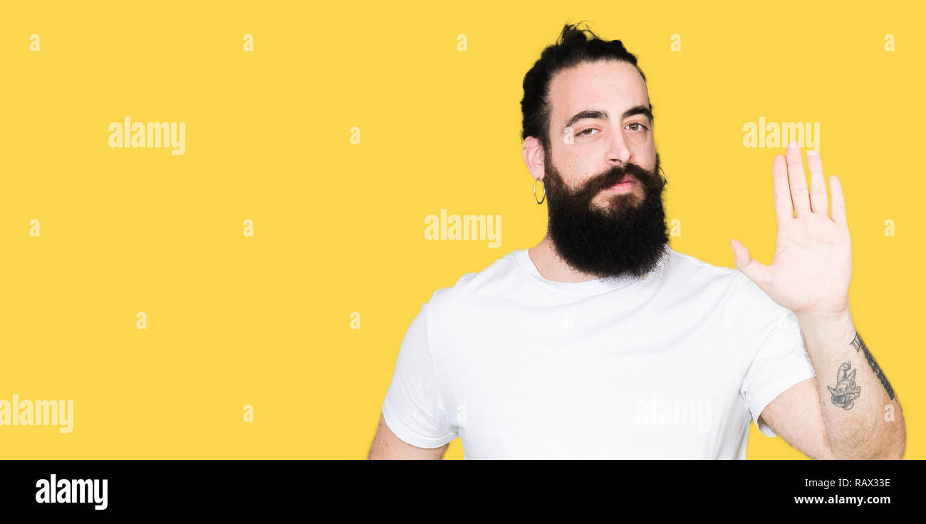 Young hipster man with long hair and beard wearing casual white t-shirt ...