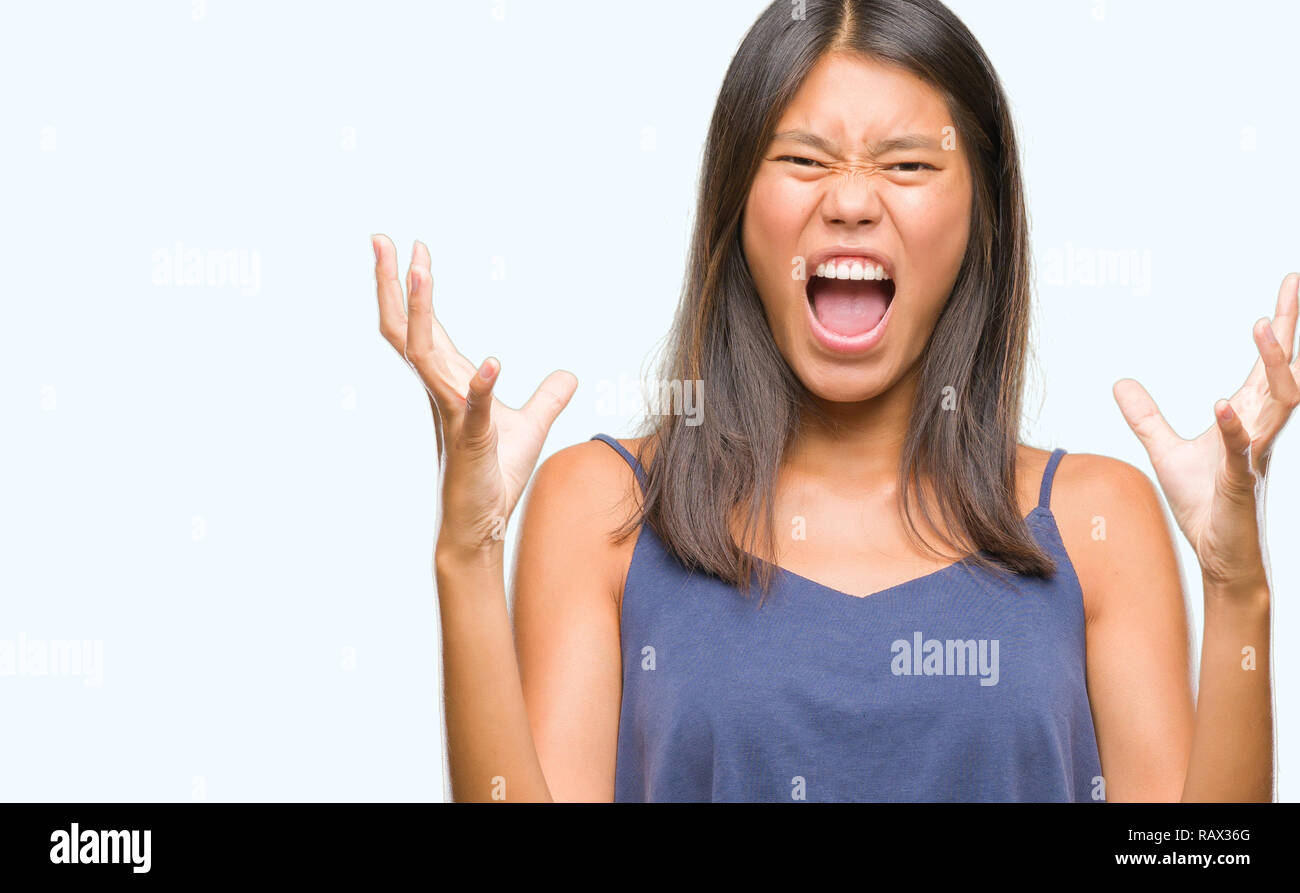 Young asian woman over isolated background crazy and mad shouting and ...