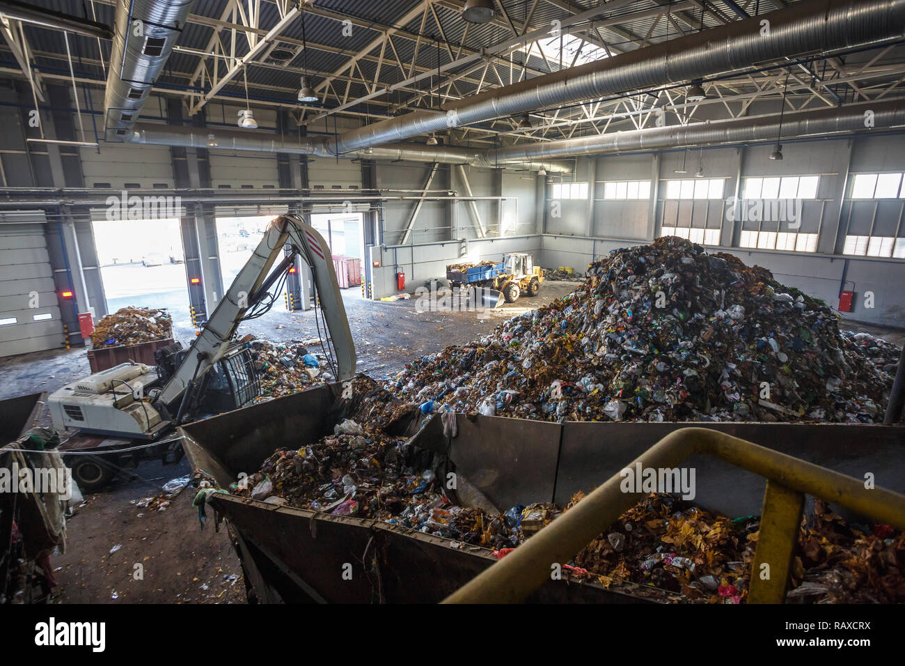 Excavator on primary sorting of garbage at waste processing plant ...