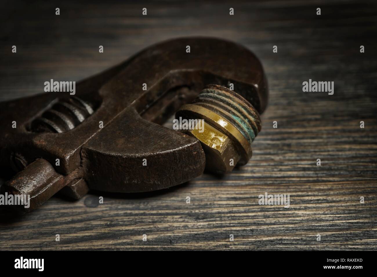 Close up vintage rusty adjustable wrench on a weathered wood background ...