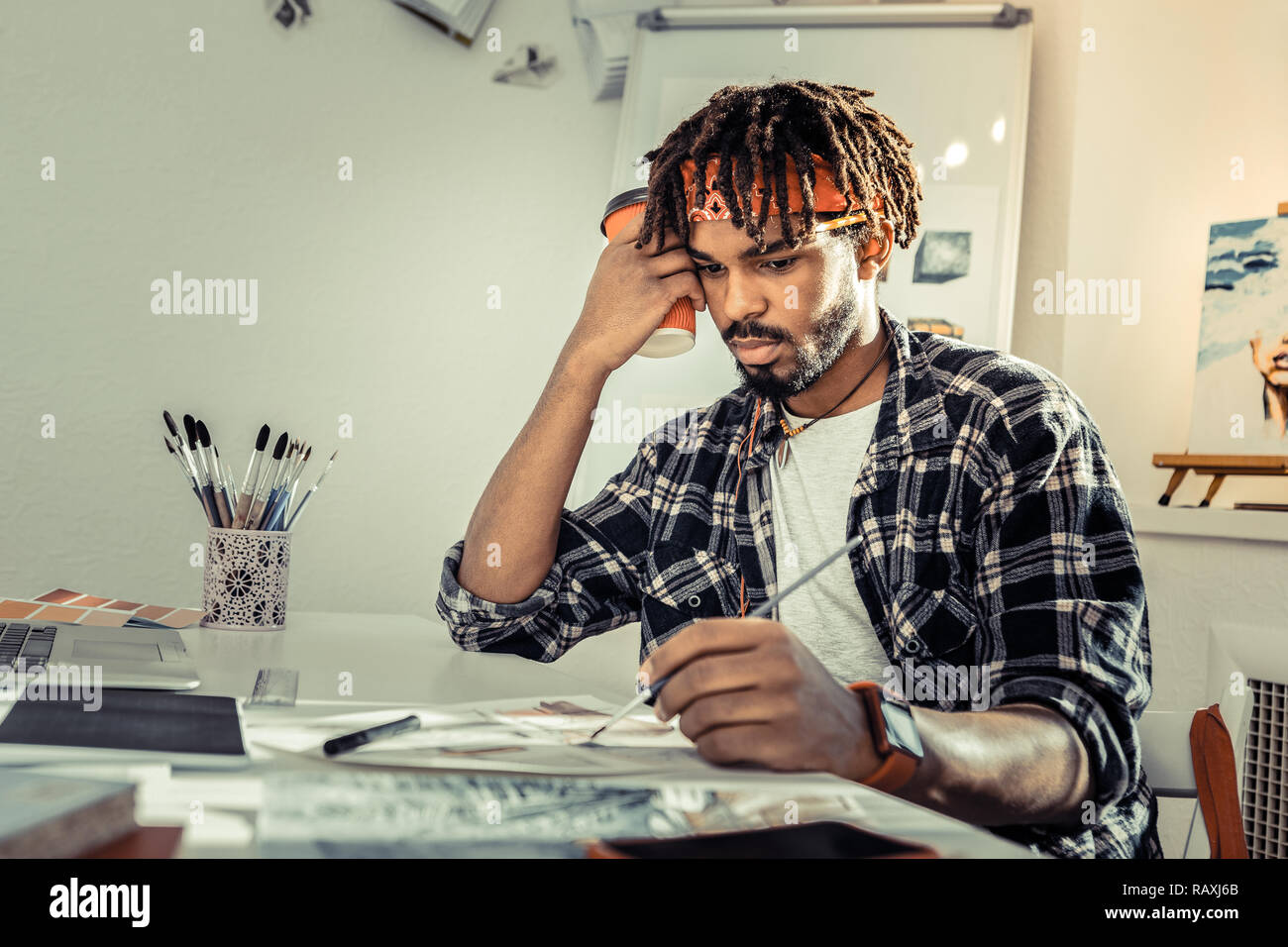 Artist with dreadlocks feeling concerned having too much work Stock ...