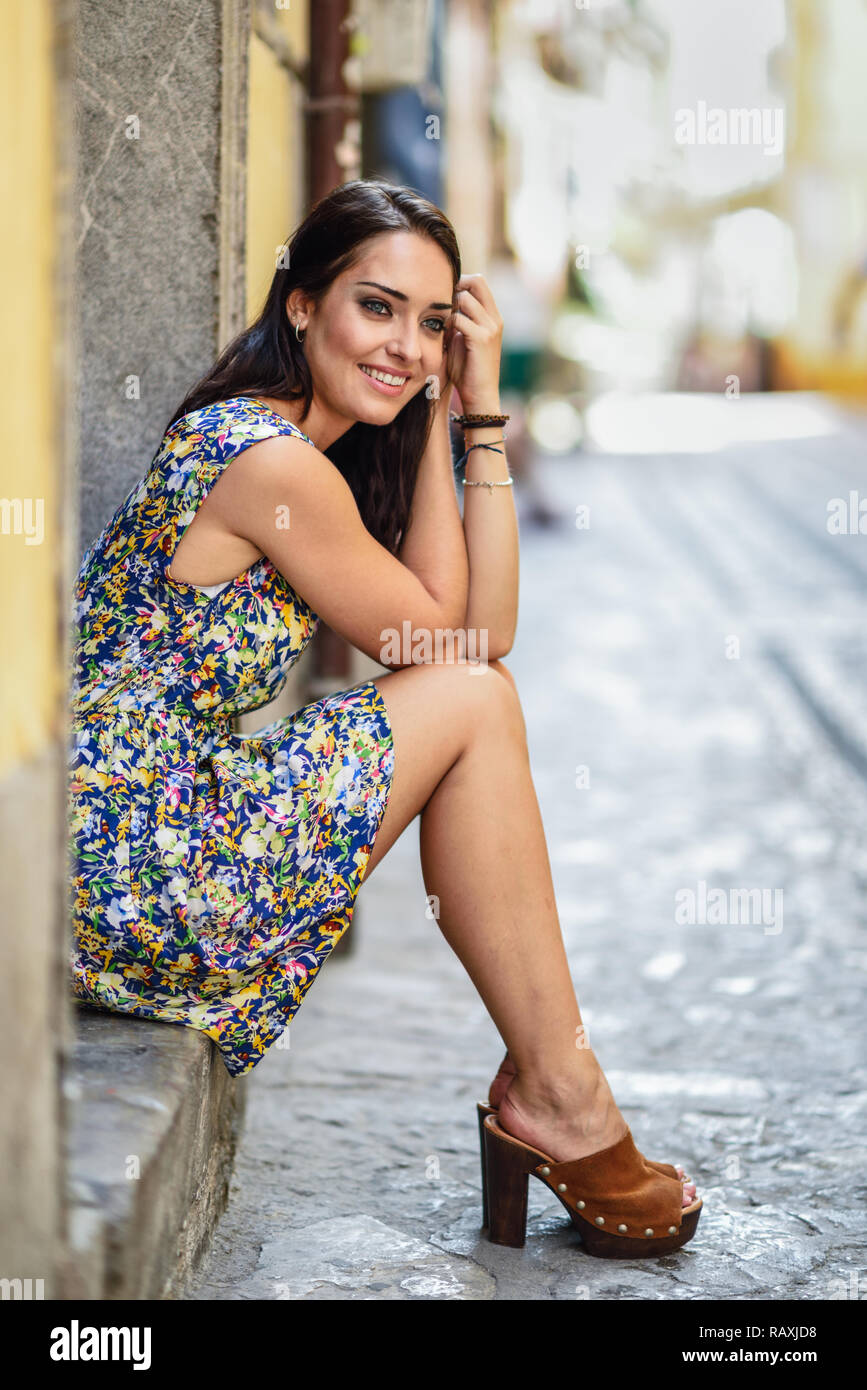 Happy young woman with blue eyes smiling sitting on urban step. Girl ...