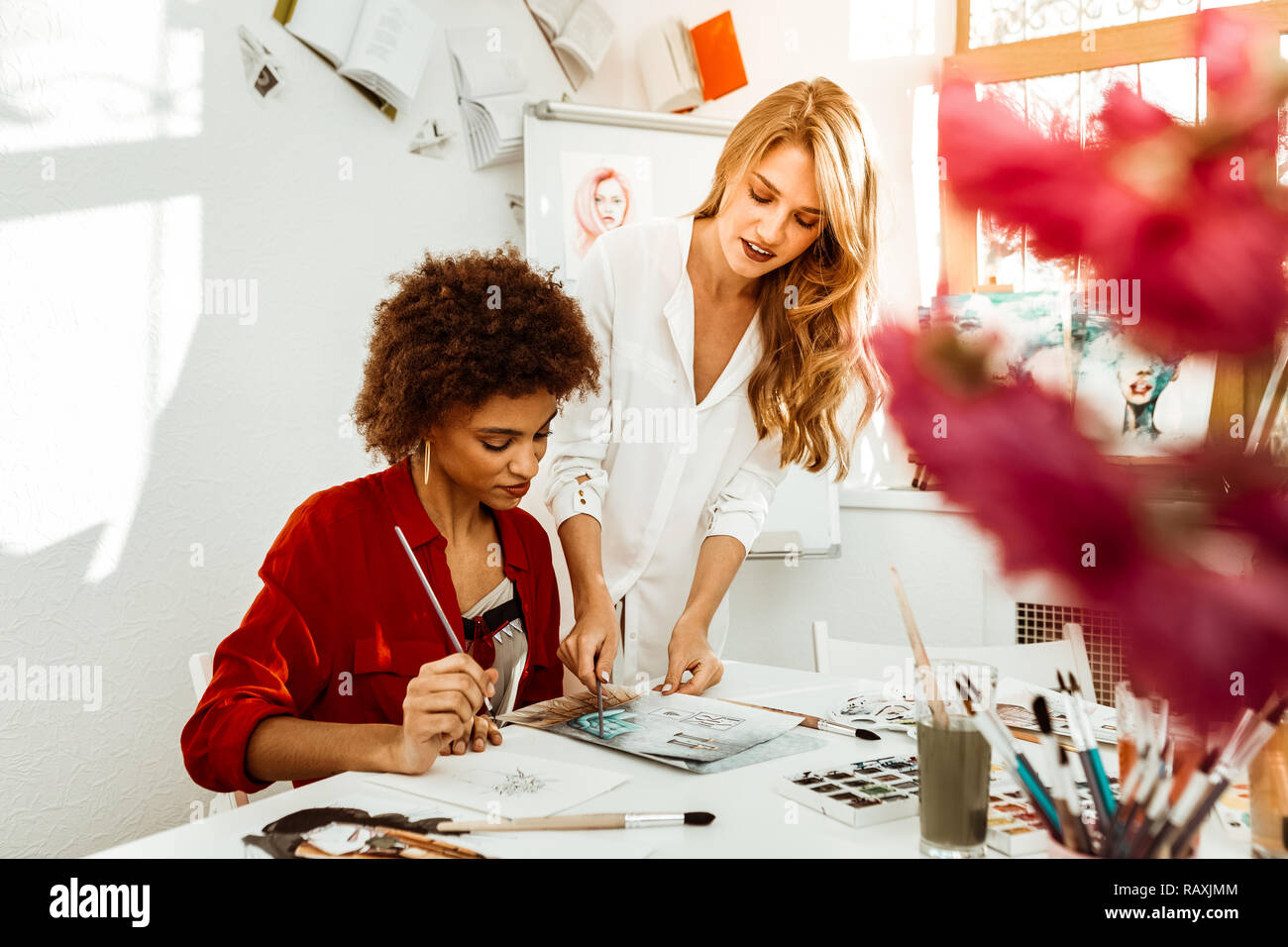 Beautiful stylish blonde-haired art teacher helping her student Stock ...