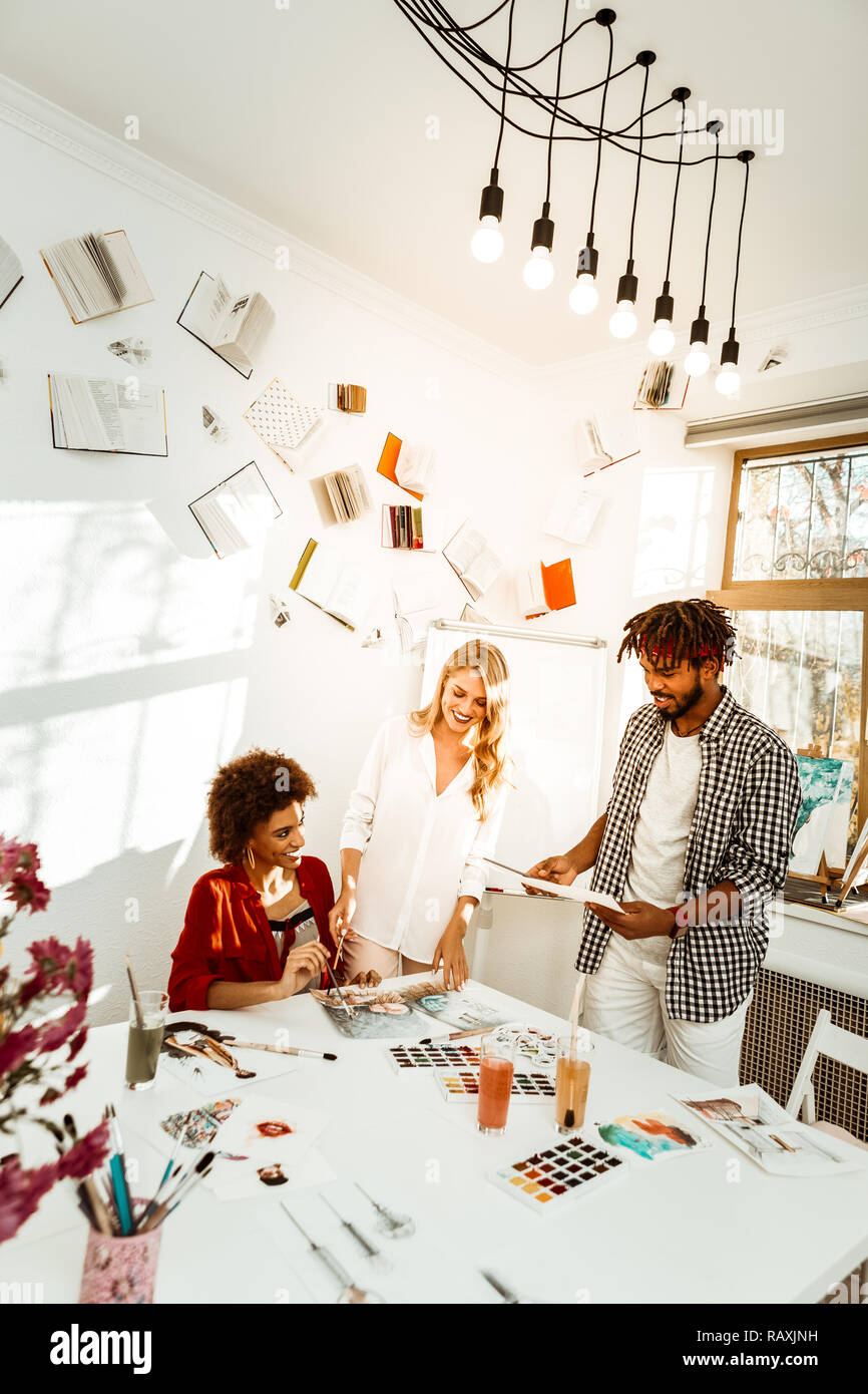 Three young artists working in light decorated studio Stock Photo - Alamy
