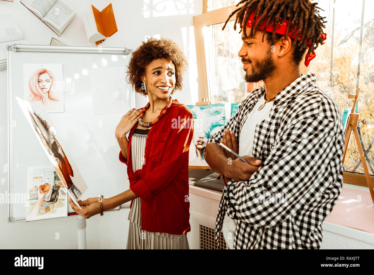 Bearded artist presenting portrait of his appealing stylish girlfriend ...