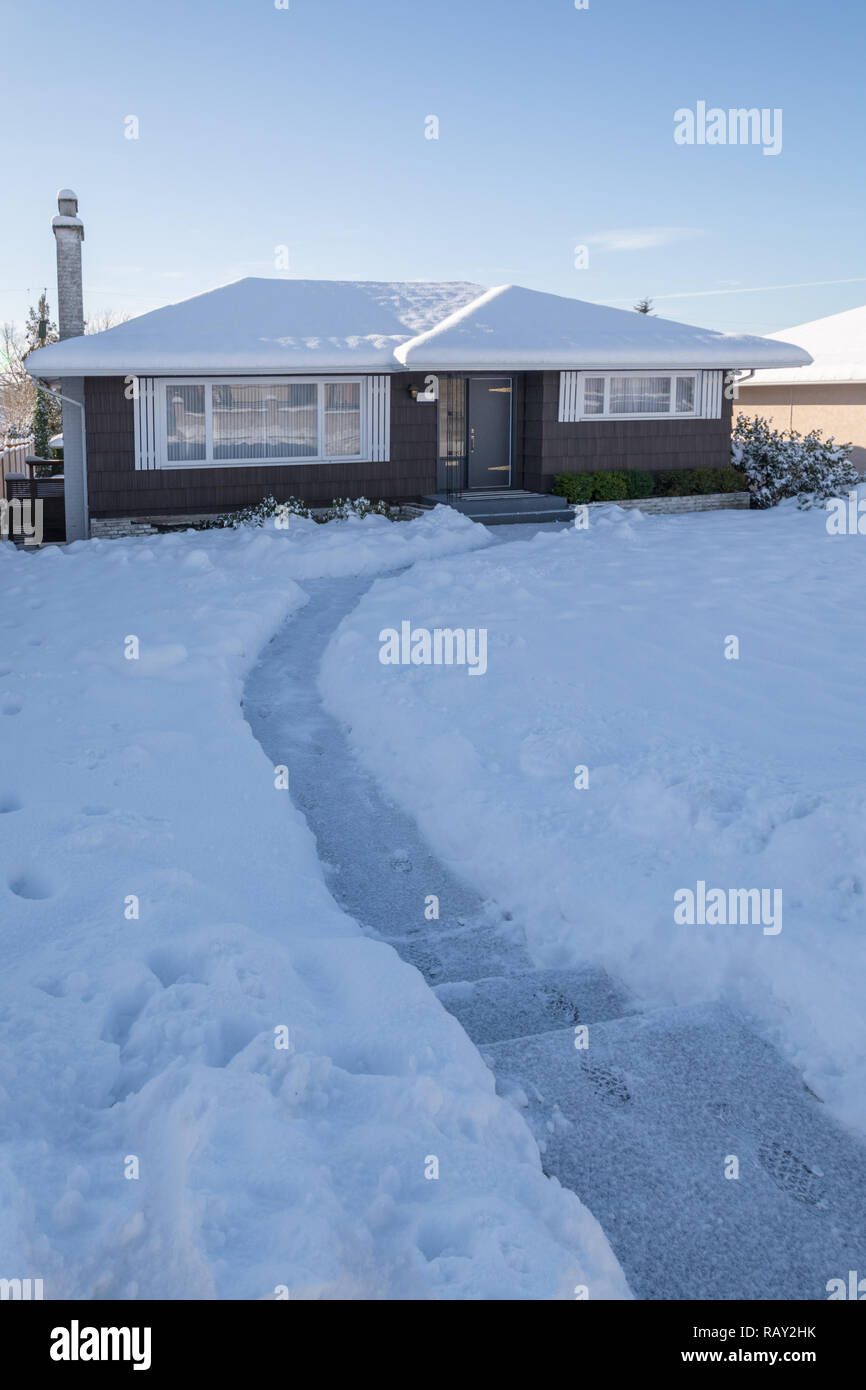 Pathway over front yard leading to average house cleaned from the snow ...