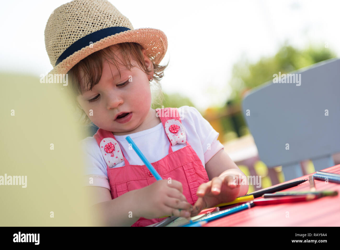 cute little girl cheerfully spending time using pencil crayons while ...
