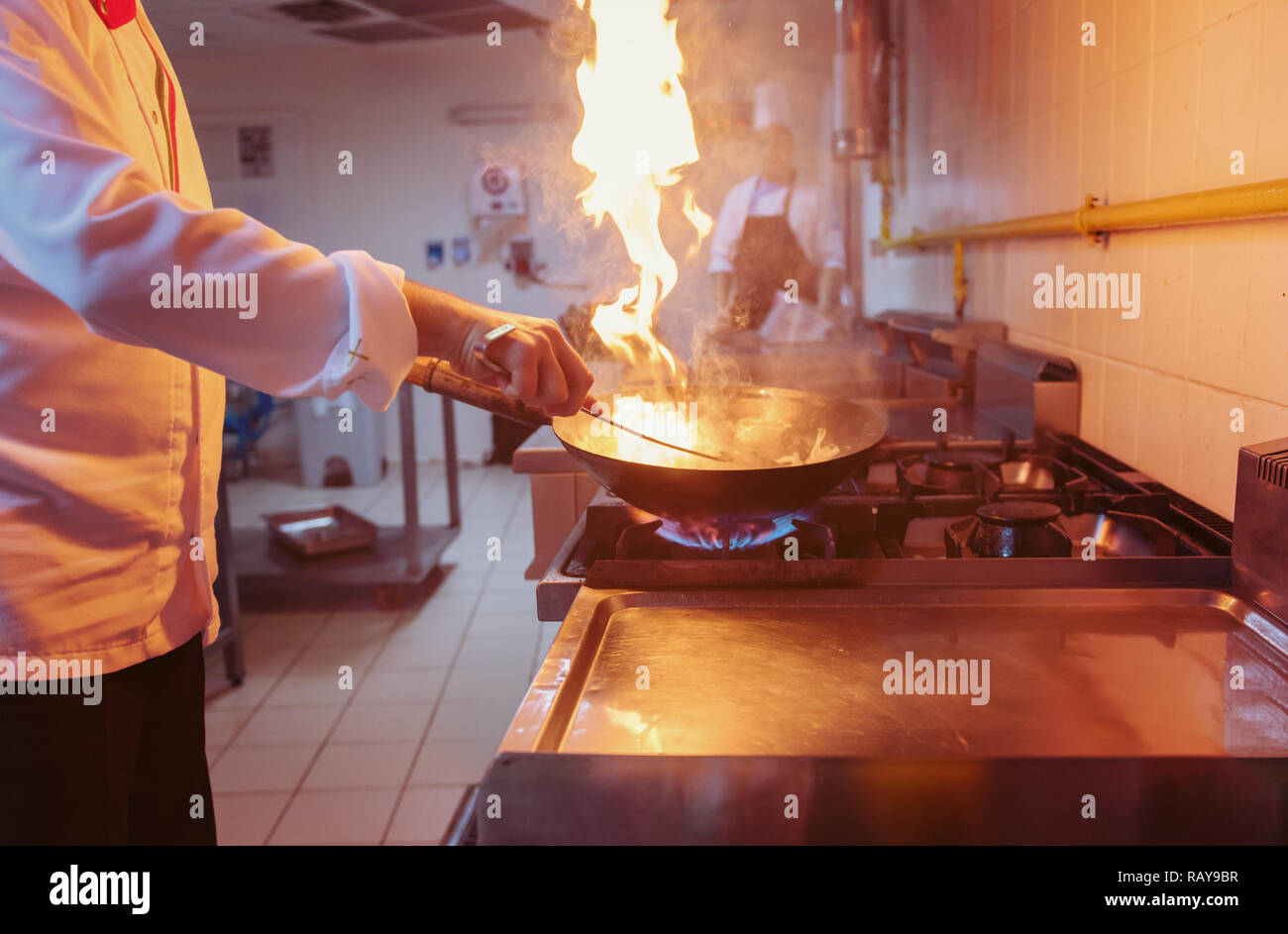 Chef cooking and doing flambe on food in restaurant kitchen Stock Photo ...