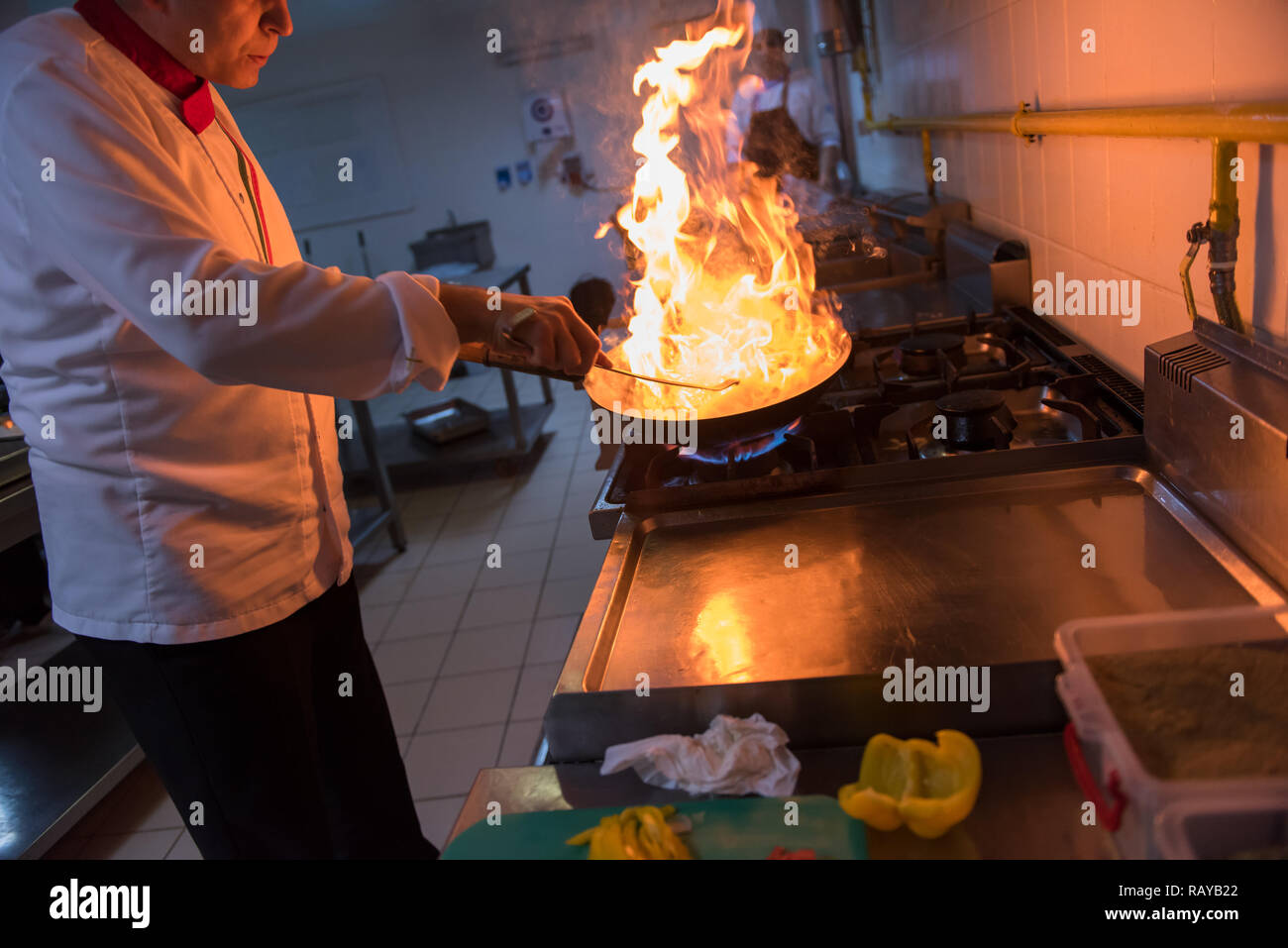 Chef cooking and doing flambe on food in restaurant kitchen Stock Photo ...
