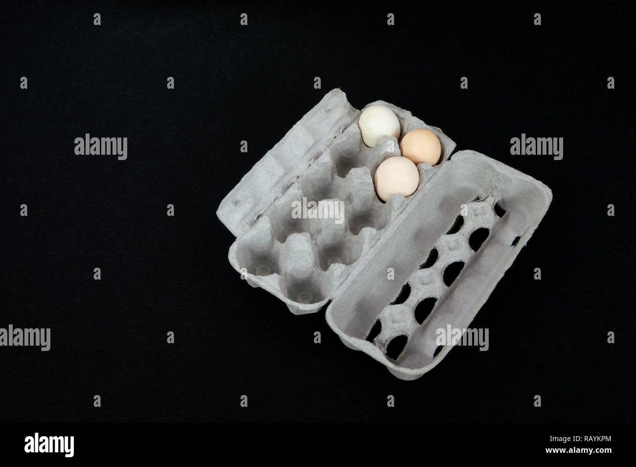 Cardboard egg box with three eggs on black felt background Stock Photo ...