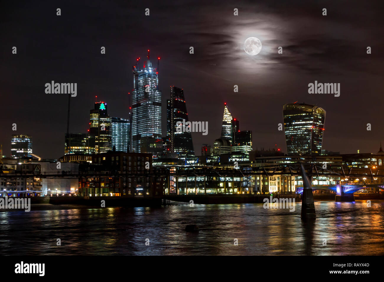 A very large moon rises from behind the towers of the City of London in ...