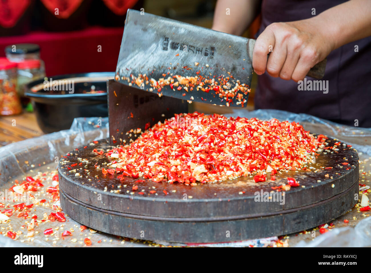 A person choppong chilli with chopping knife on the wooden chopping ...
