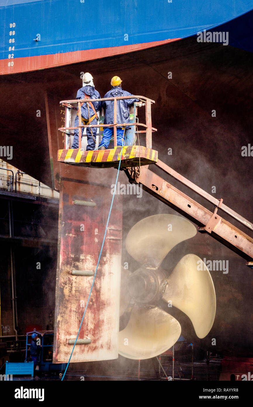 Dock workers at work on a vessel hull in a ship repair drydock Stock ...