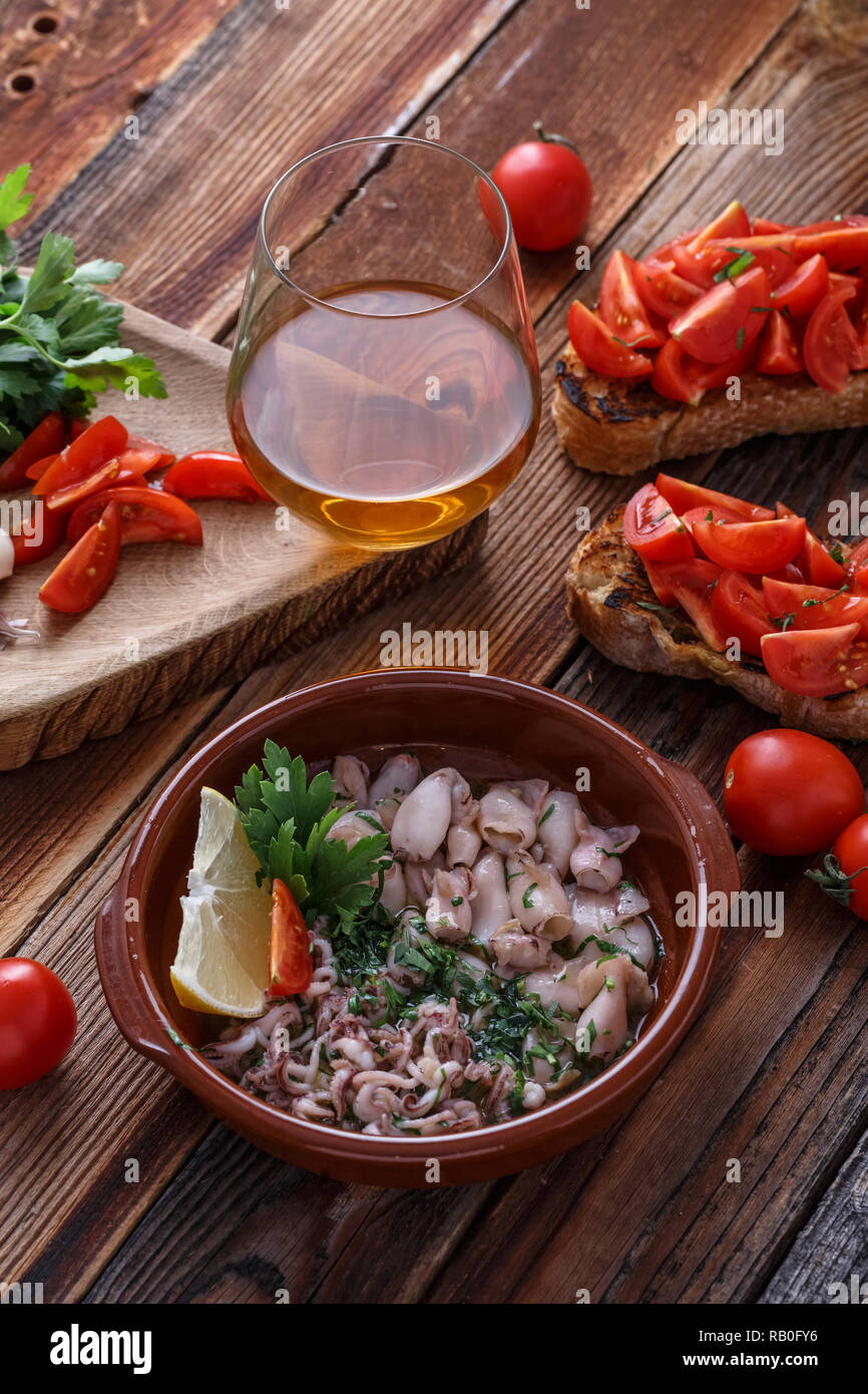 Baby calamari in olive oil with bruschettas and wine Stock Photo - Alamy