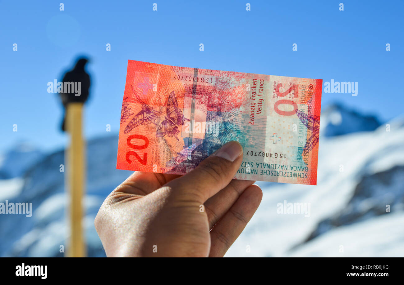 Hand holding a 20 Swiss franc banknote with snow mountain background ...