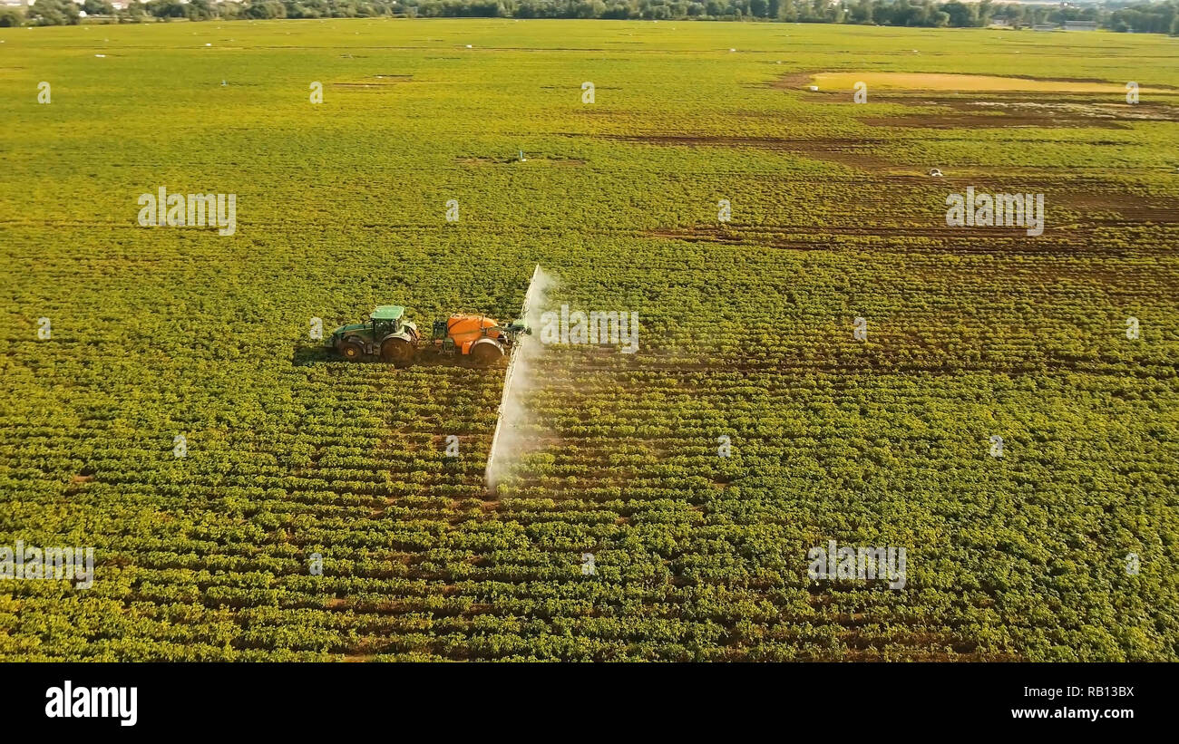 Aerial view tractor spraying chemicals on large green field. Spraying ...