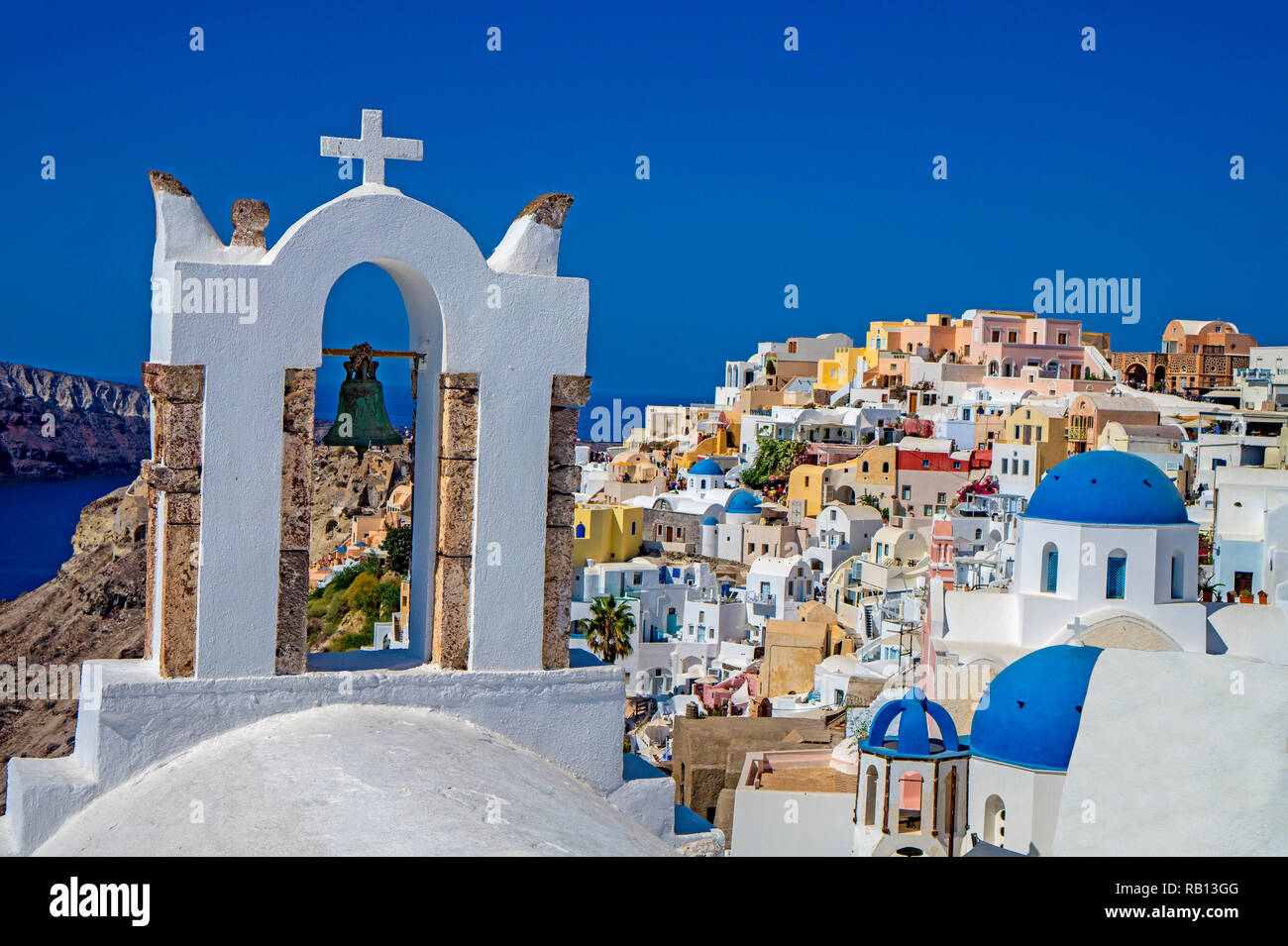 Colorful city of Oia in Santorini greece with a bell cross and domes ...