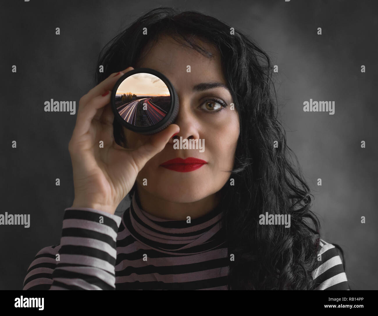 Brunette woman with camera lens in her eye, with long exposure ...