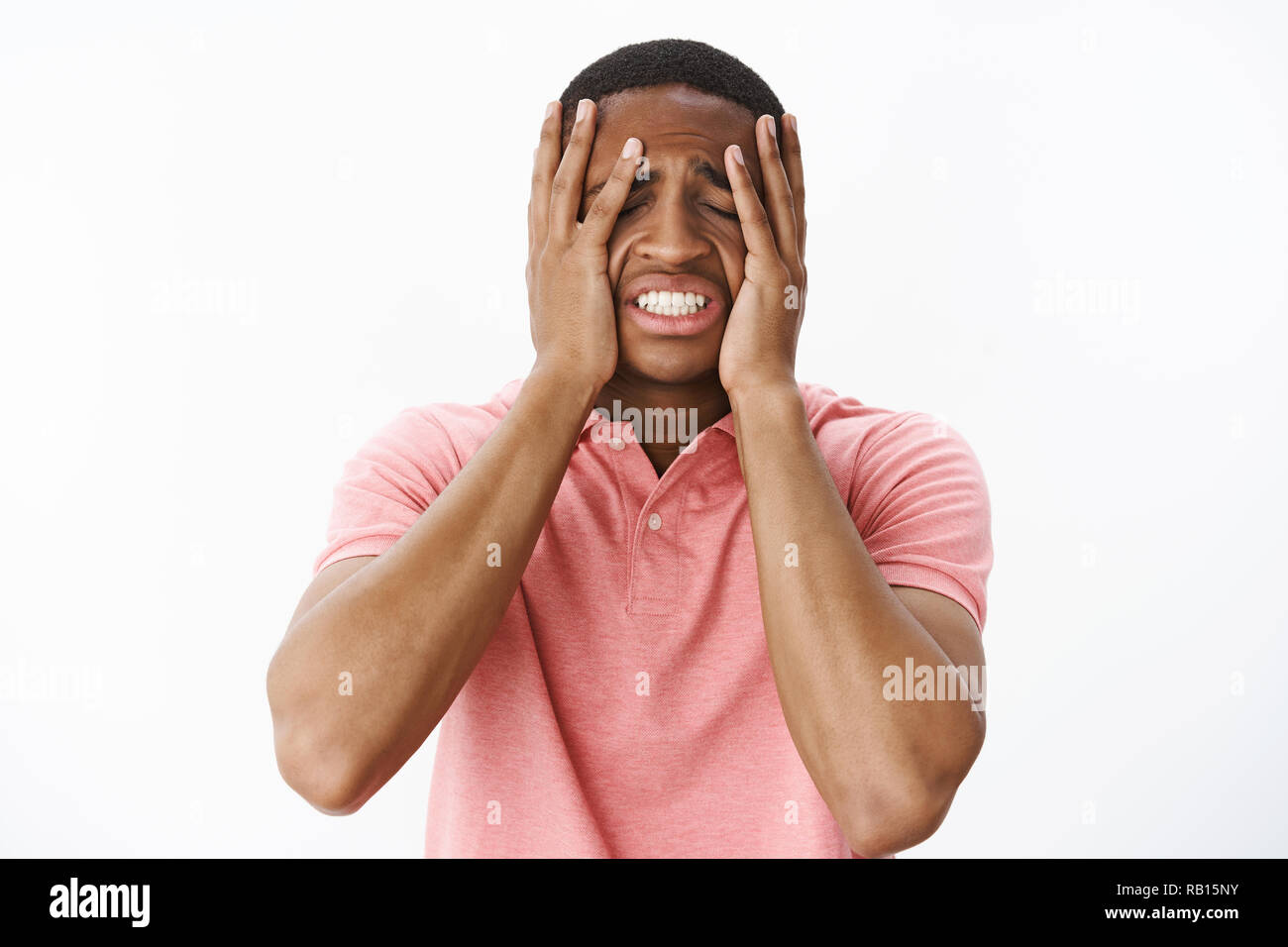 Guy suffering from guilt and sorrow pressing hands to face clenching ...