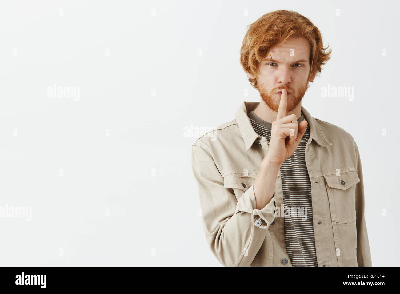 Shh leave it secret. Portrait of mysterious good-looking young redhead ...