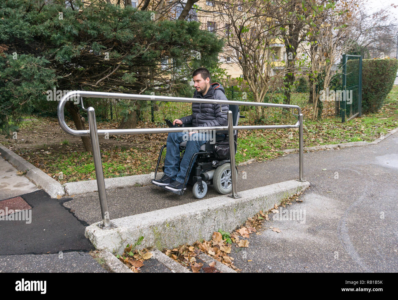 Man in a wheelchair using a ramp next to stairs Stock Photo - Alamy