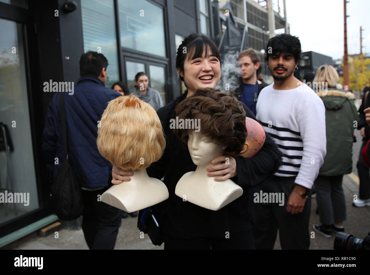 A hairdresser carries some wigs backstage during the Xander Zhou at ...