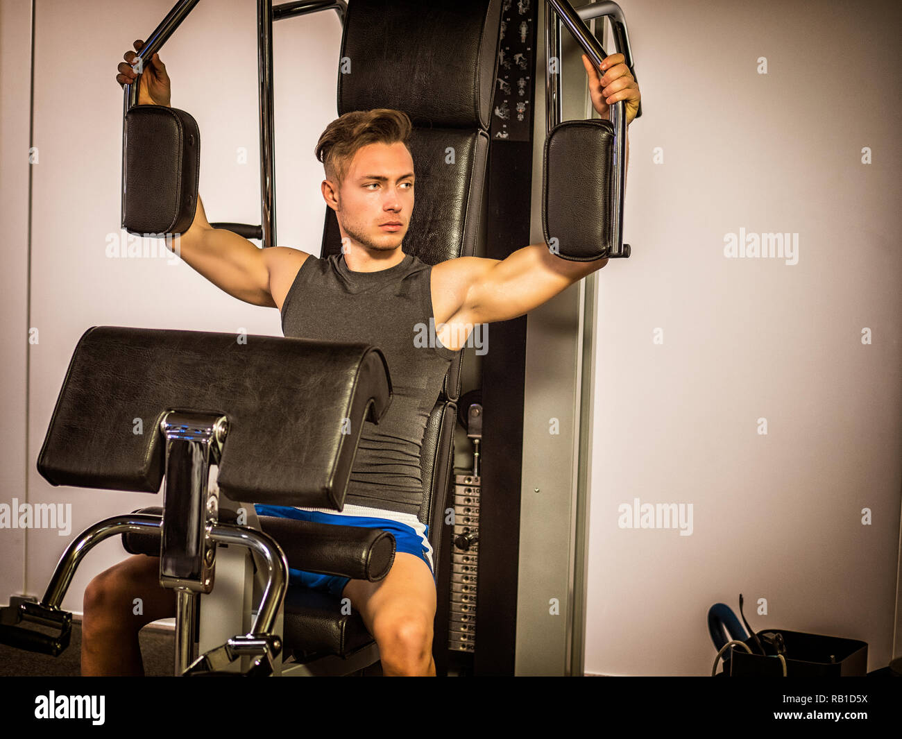 Muscular young man, training pecs on gym cable machine Stock Photo - Alamy