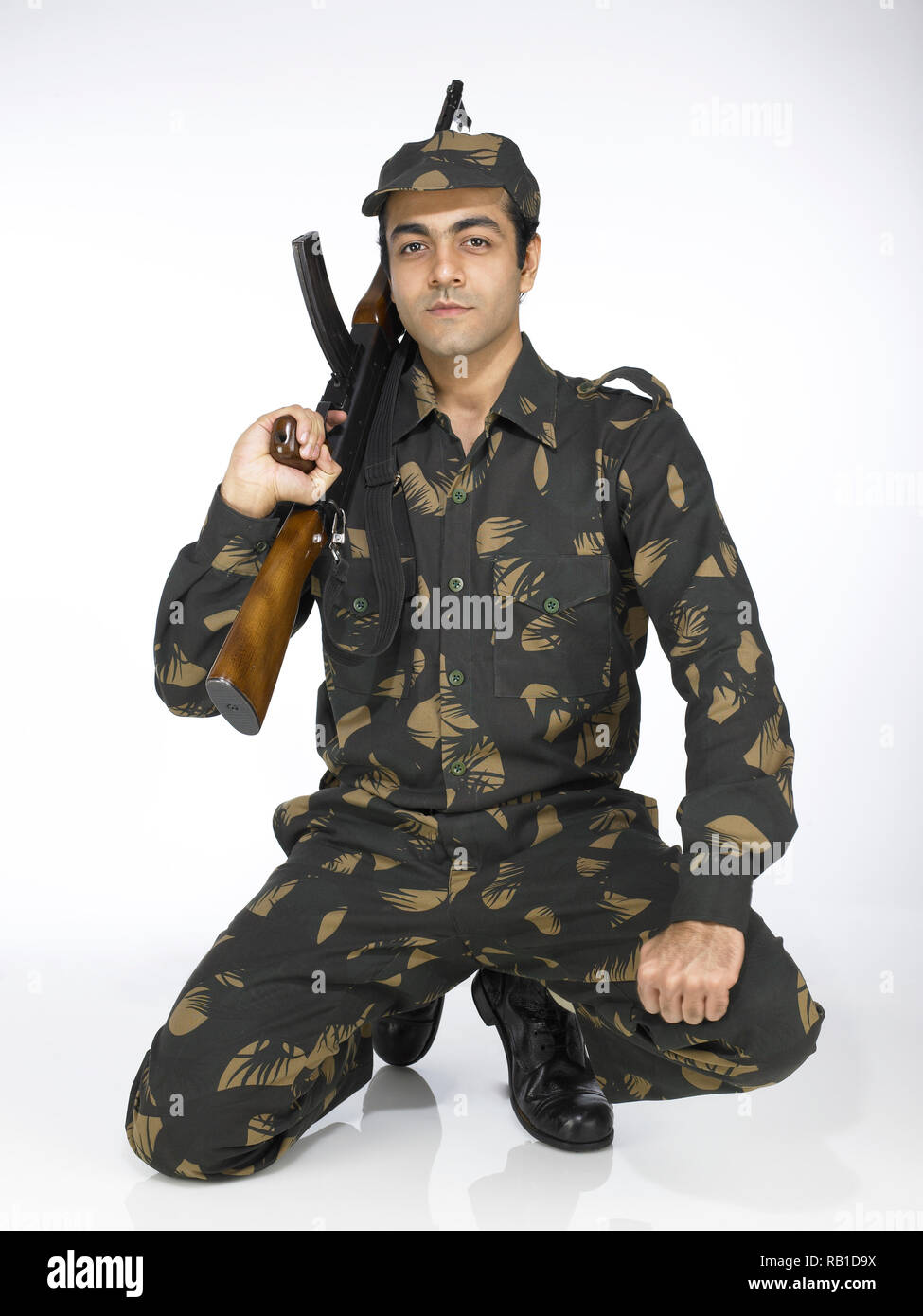PORTRAIT OF INDIAN SOLDIER DRESSED IN UNIFORM AND HOLDING AMACHINE GUN ...