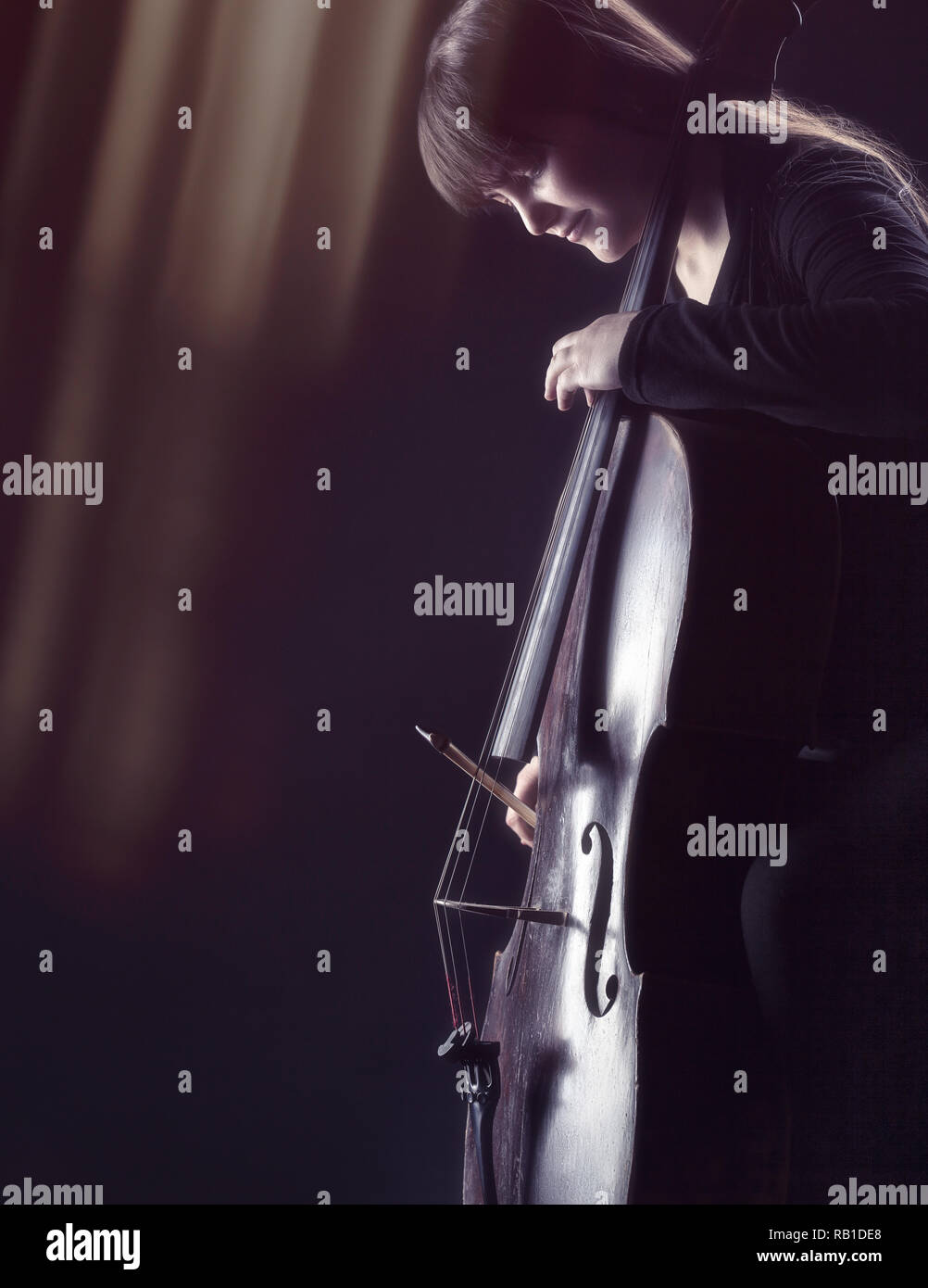 Close-up of cellist playing classical music on cello against a black ...