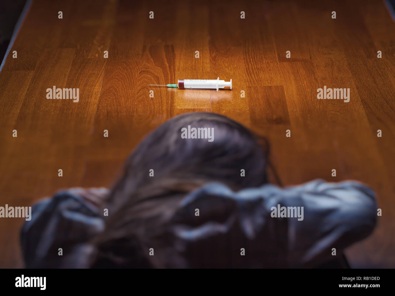 Close-up of a syringe with drugs beside lies a young woman. Focus on ...