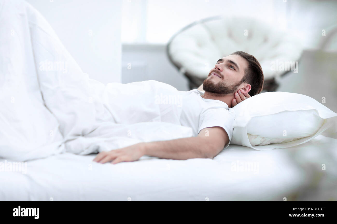 tired man resting on a comfortable bed Stock Photo - Alamy