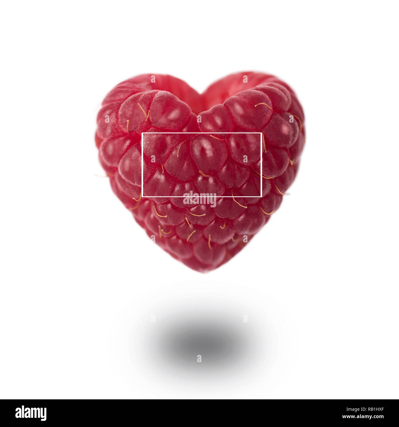 Raspberry in the shape of a heart with a shadow on a white background ...
