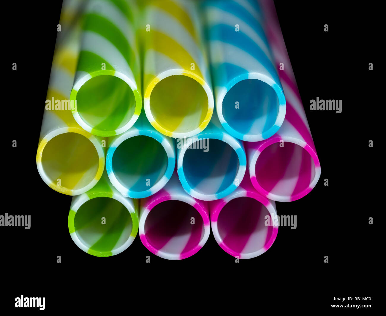 Colourly striped plastic drinking straws, black underground background ...