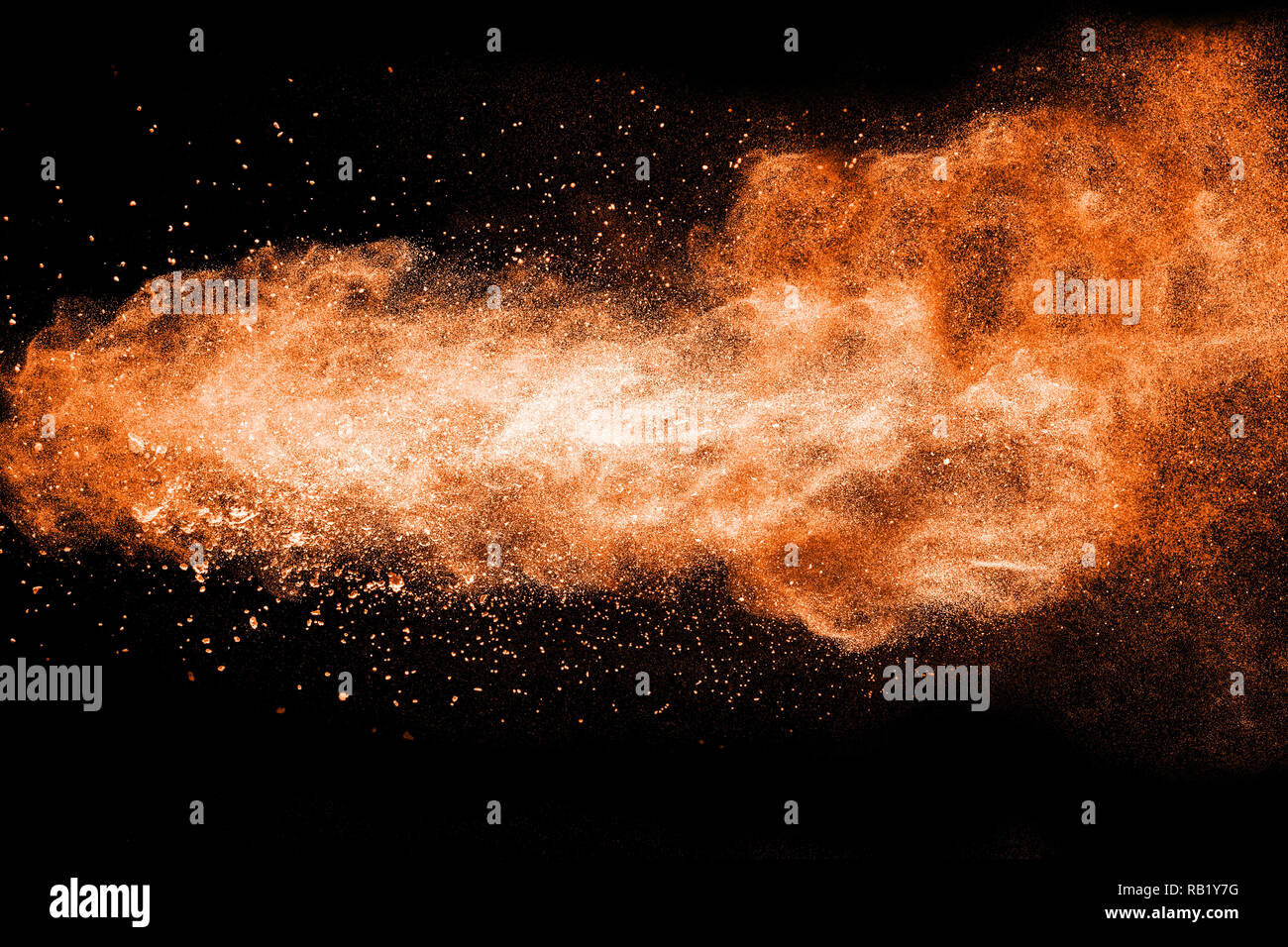 Abstract explosion of orange dust on black background. Freeze motion of ...