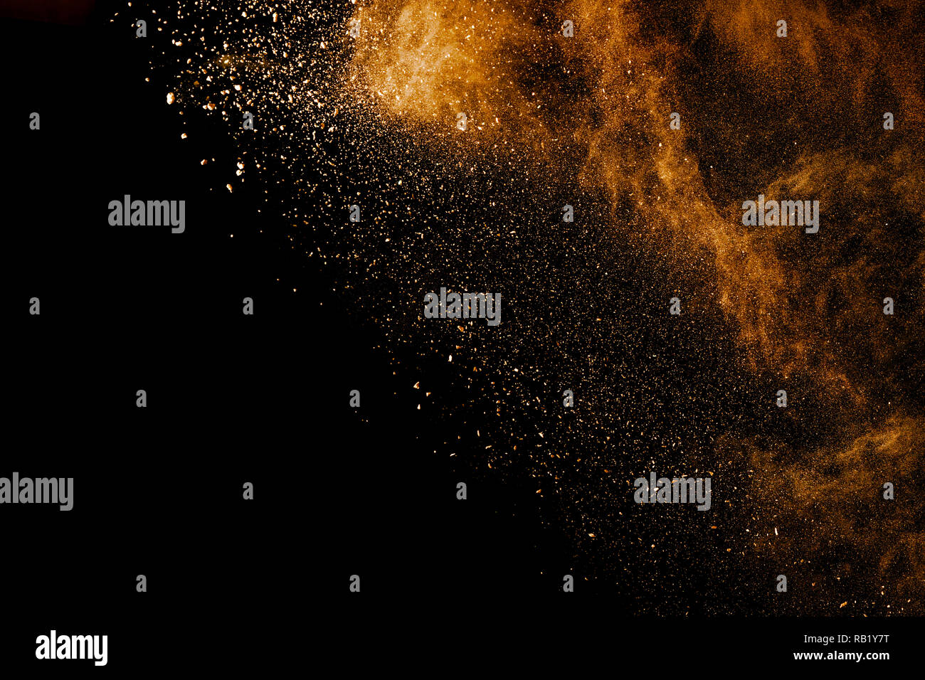 Abstract explosion of orange dust on black background. Freeze motion of ...