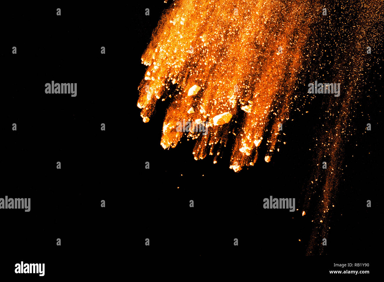 Abstract explosion of orange dust on black background. Freeze motion of ...