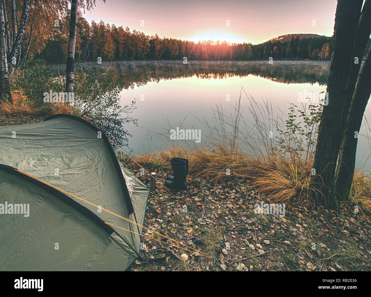 Green camping tent on the lake bank in early morning. Daybreak sun ...