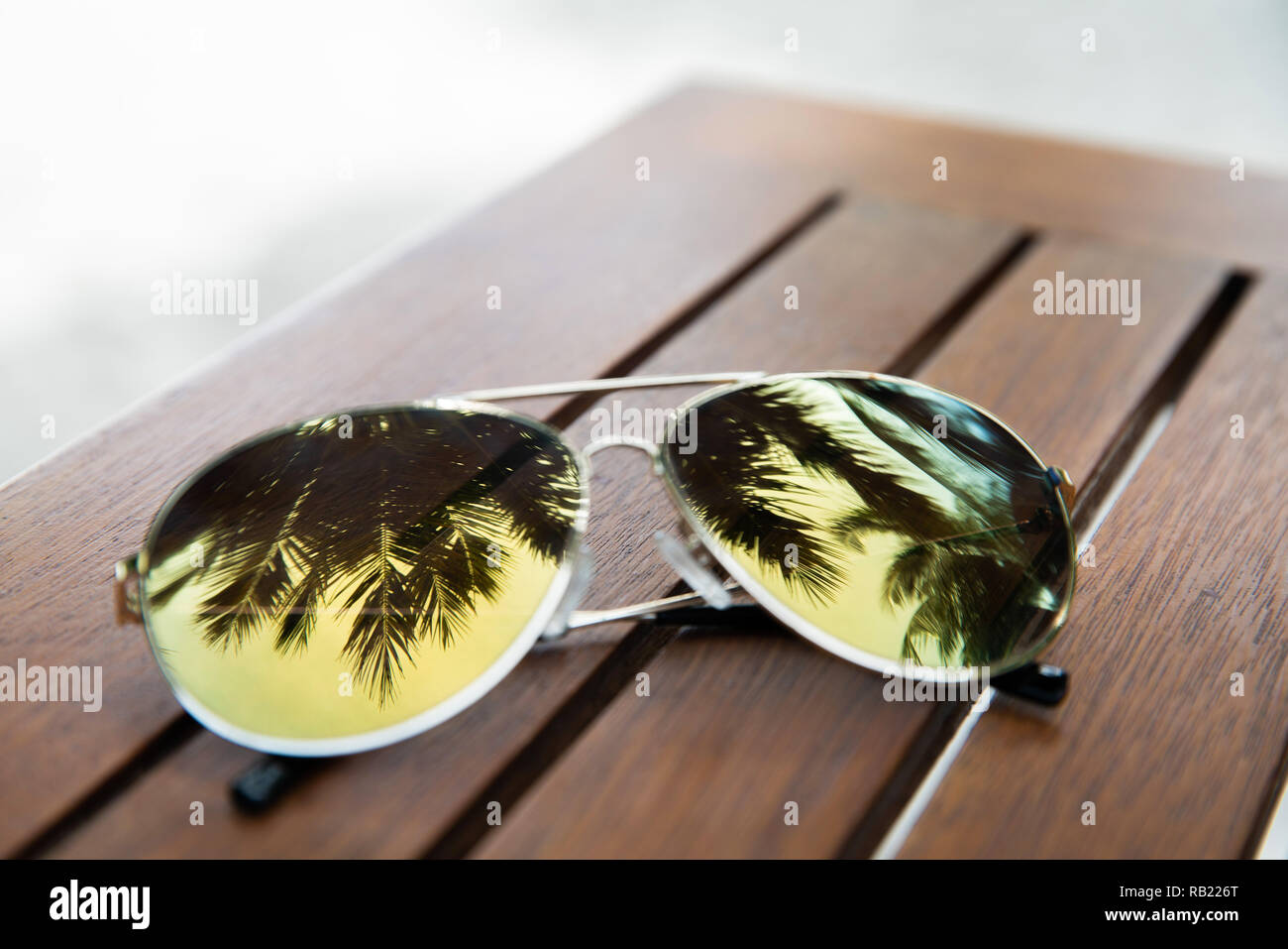 Sunglass on wood table and reflection coconut tree, near sea nature ...