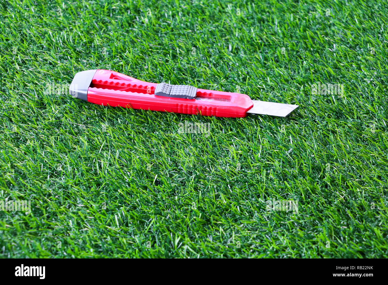 red cutter knife on artificial grass background Stock Photo - Alamy