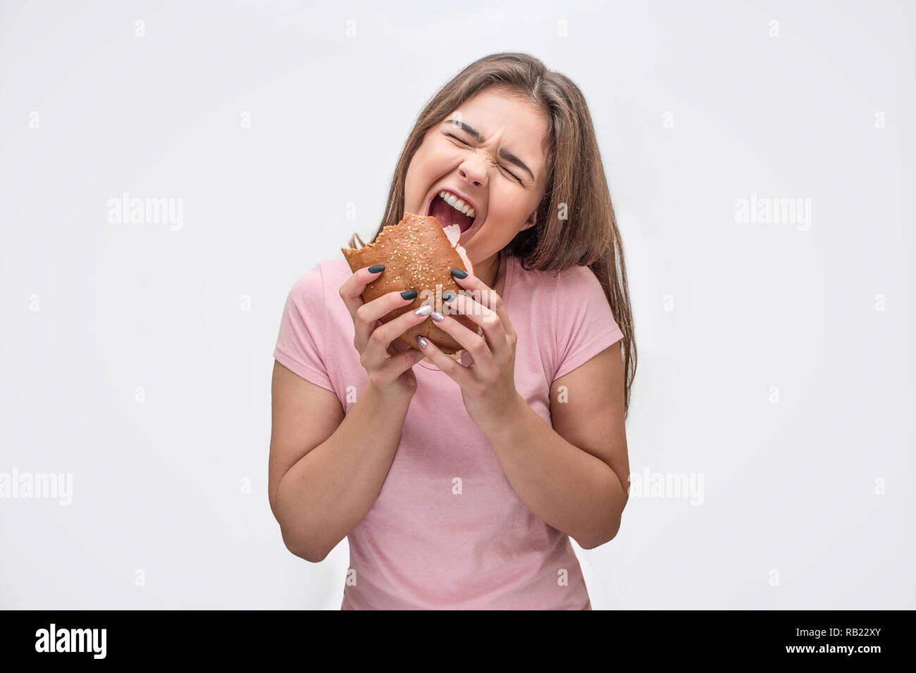 Happy young woman hold burger. She is going to eat it. Model is ...