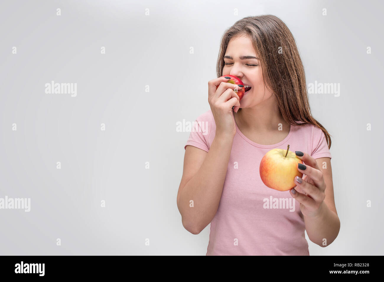Picture of young woman bite piece of apple. She looks on camera ...