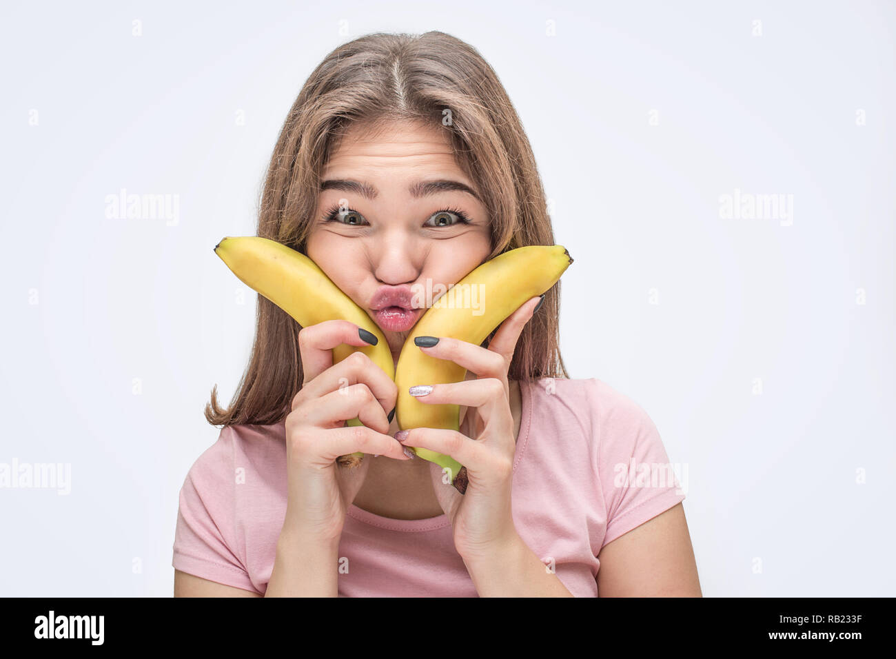 Playful young woman lok on camera. She press cheeks with it. Model ...