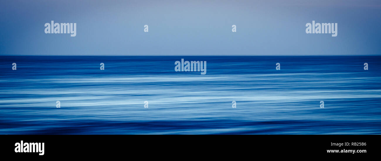 artistic image with blurry and stretched ocean blue water in long ...