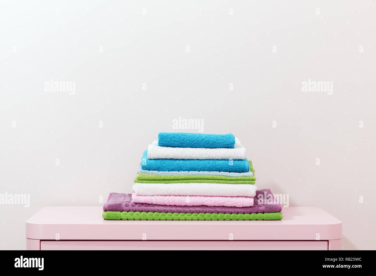 On the chest lies a stack of stacked colorful towels Stock Photo - Alamy