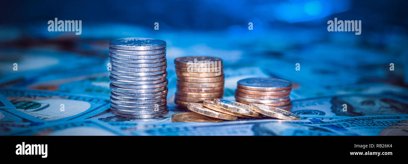 Stacks of coins on the background of one hundred dollar bills. Dark ...