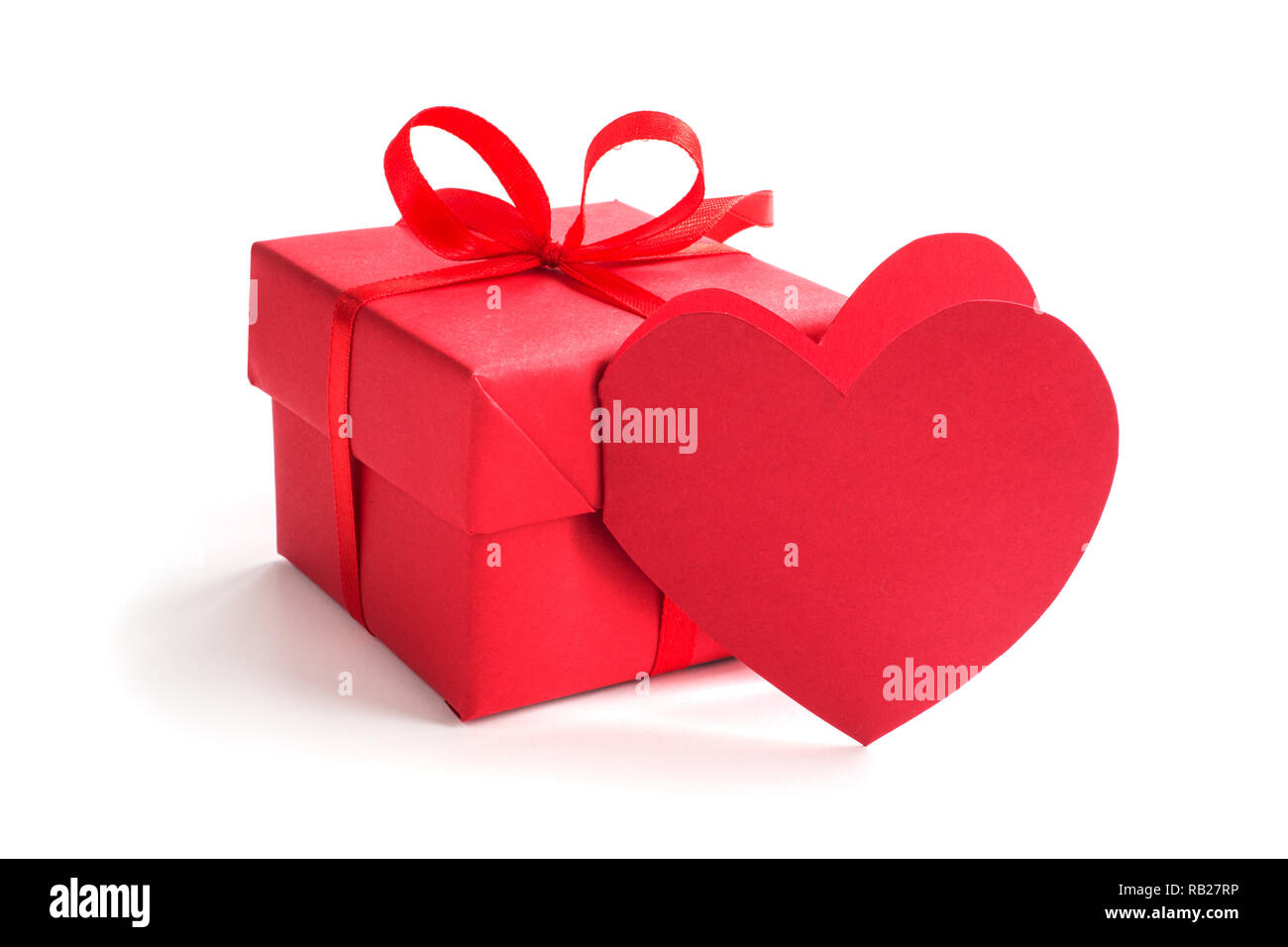 Small red gift box with ribbon bow and paper heart shaped greeting card ...
