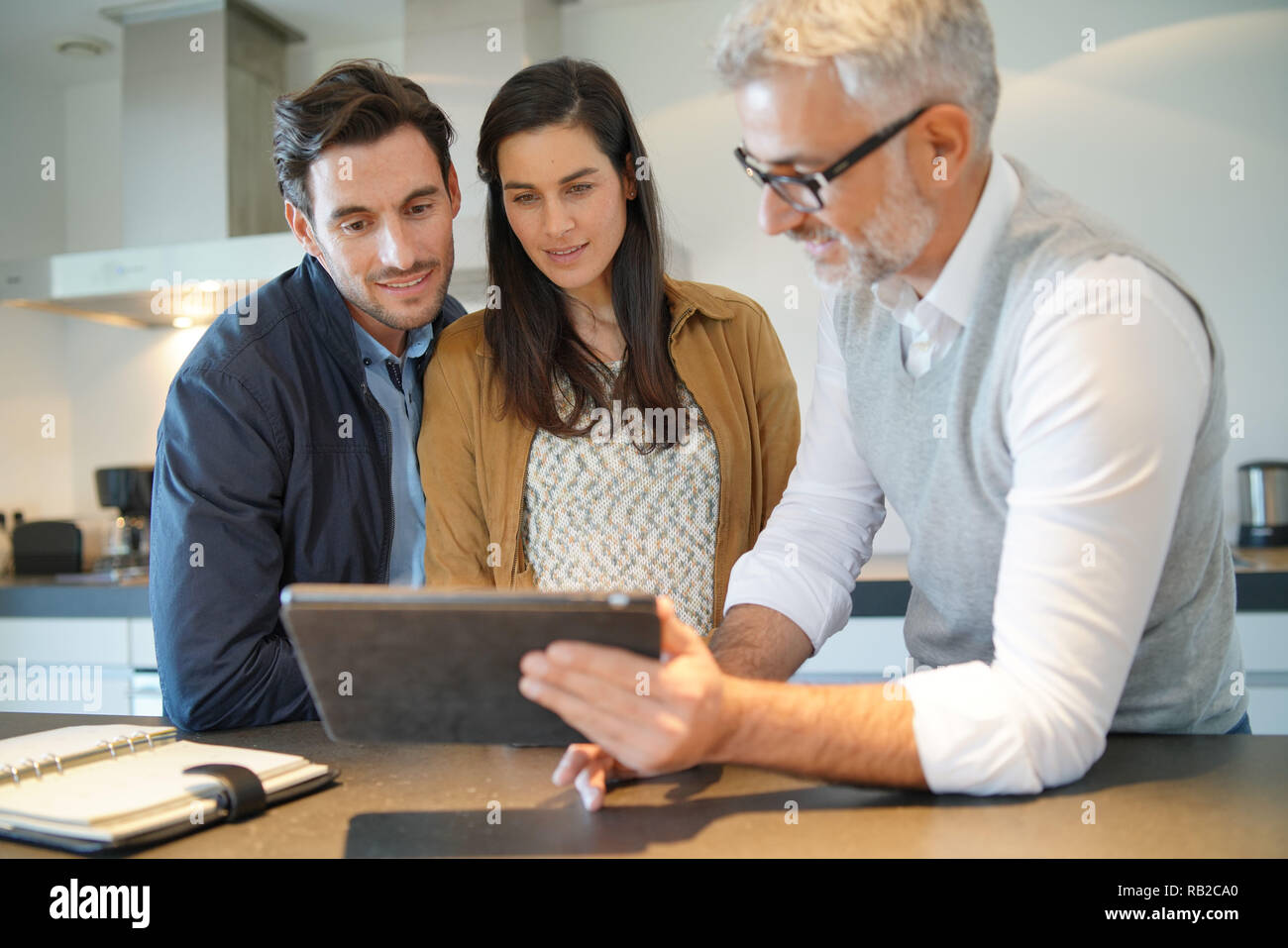 Kitchen salesman going through ideas with potential buyer couple Stock ...