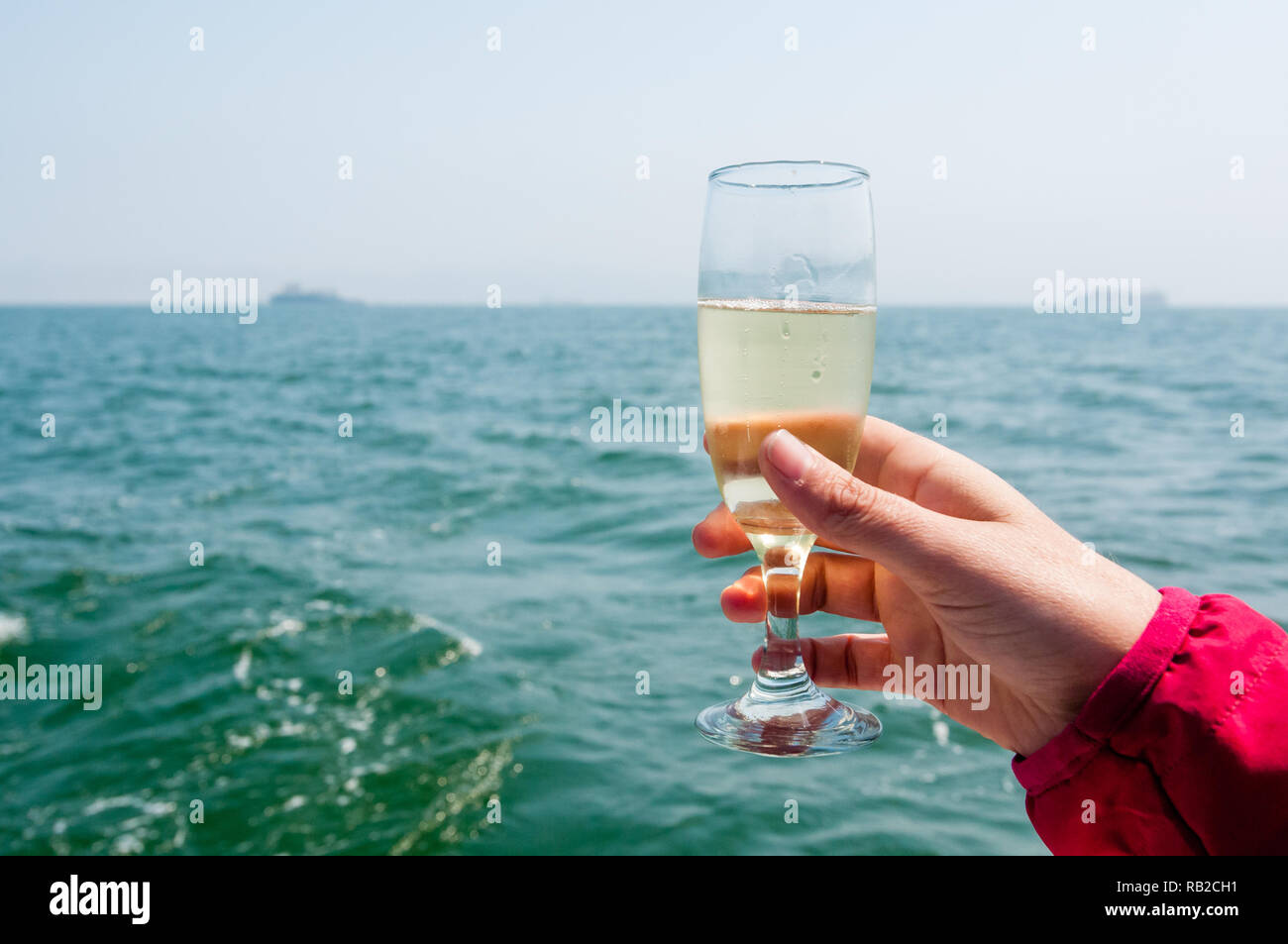 Woman raising glass of champagne for a toast, ocean, water Stock Photo ...
